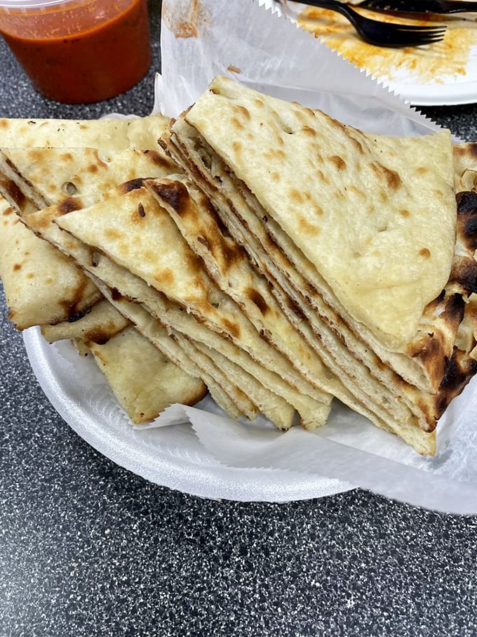 Naan bread stacked like delicious playing cards, each piece bearing the perfect char marks of a properly hot tandoor oven.