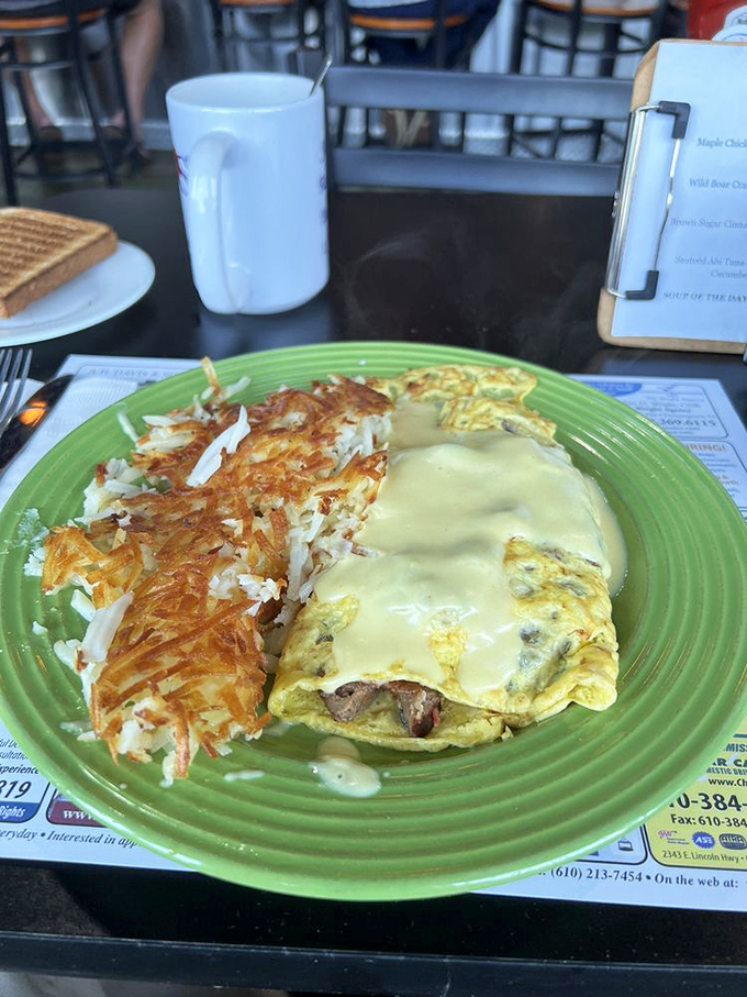 A vibrant green plate showcasing an omelet draped in cheese alongside perfectly crispy hash browns. The kind of breakfast that makes you rethink your life choices.