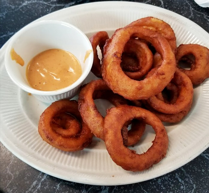 Onion rings with the perfect crunch-to-softness ratio, accompanied by a dipping sauce that makes ketchup seem like amateur hour.