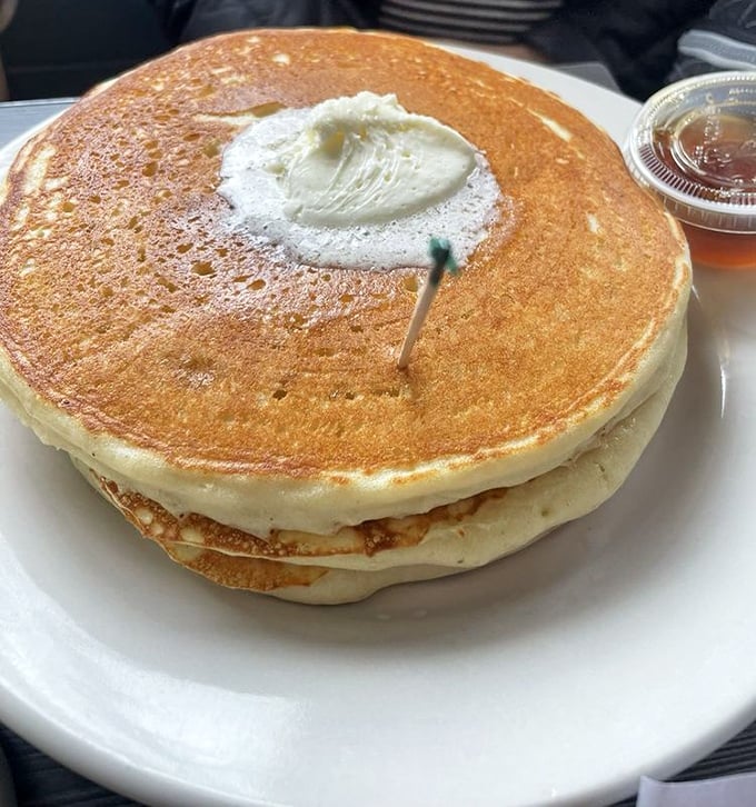 Pancakes stacked like fluffy clouds, waiting for their maple syrup thunderstorm to begin.