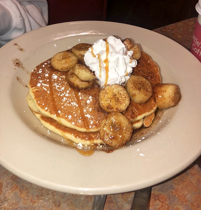 Pancakes topped with caramelized bananas and whipped cream that don't just satisfy hunger—they create a moment of pure, syrup-drizzled bliss.