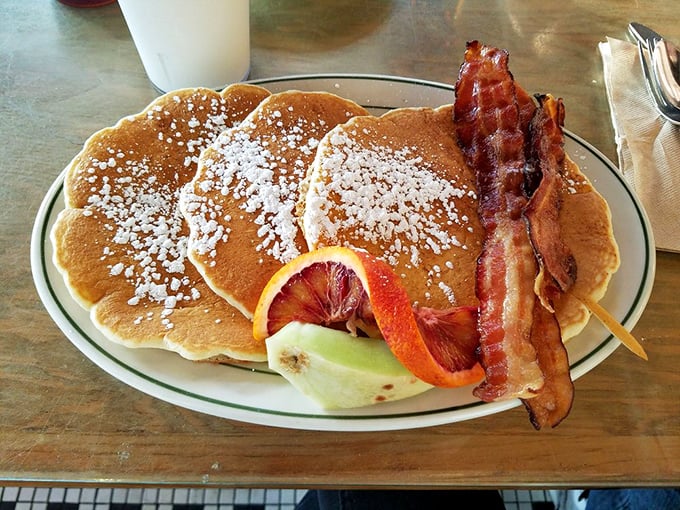 Pancakes dusted with powdered sugar and paired with perfectly crisp bacon&mdash;breakfast's dynamic duo performing their greatest hits on a simple white plate.