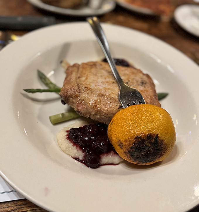 This isn't just any pork chop &ndash; it's a masterpiece of careful cooking, accompanied by a charred orange that hints at the chef's attention to detail.