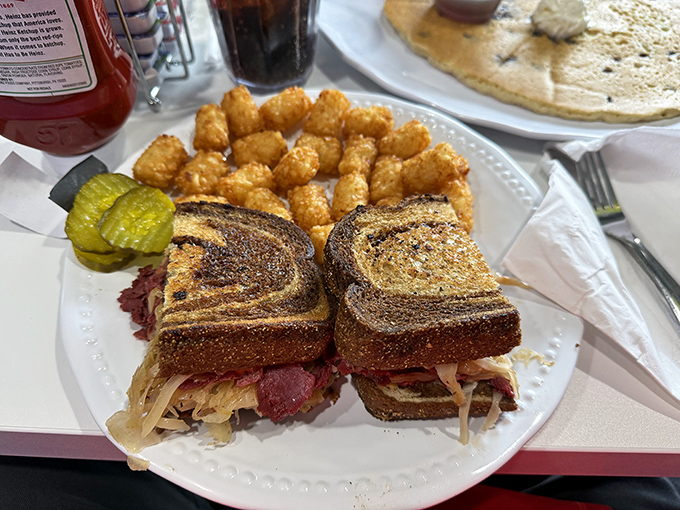 A proper Reuben requires architectural integrity, flavor balance, and tater tots as neighbors. This sandwich checks all the boxes with swagger.