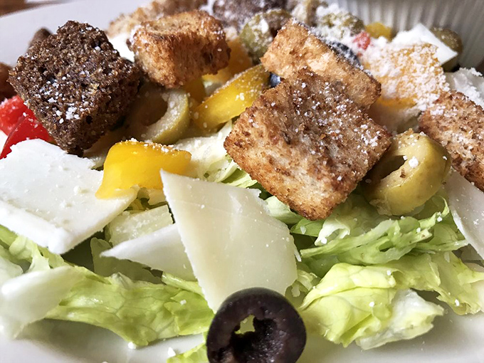 The house salad offers a crisp counterpoint to pizza indulgence, with croutons substantial enough to earn their place at the table.