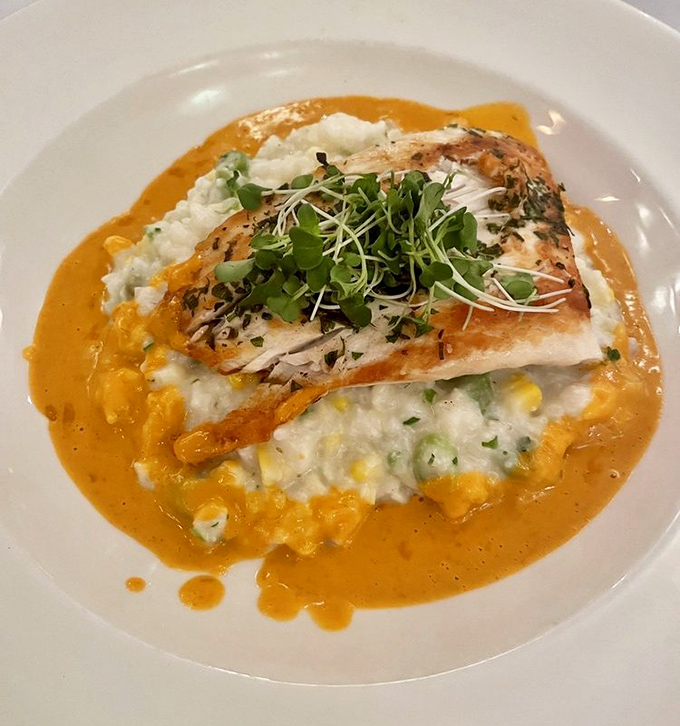 The sea bass arrives like a work of art, perched atop creamy risotto with a sunset-colored sauce that tastes like a chef's love letter to the ocean.