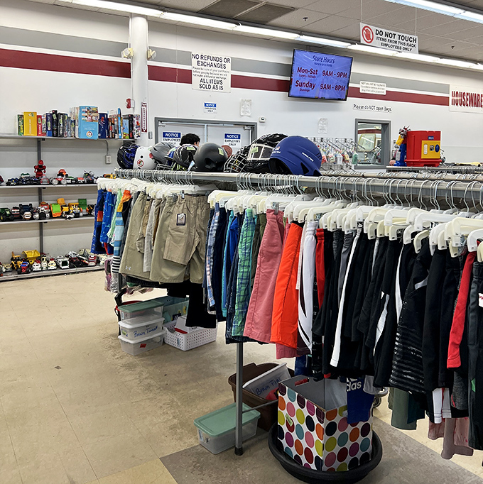 Sports equipment and children's clothes coexist in organized chaos. Hockey helmets stand guard over a rainbow of pint-sized fashion statements.