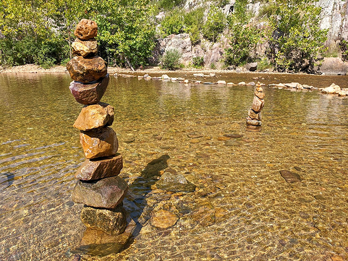 Balanced rock sculptures emerge from crystal-clear waters. Visitors create these temporary monuments, adding human artistry to nature's masterpiece.