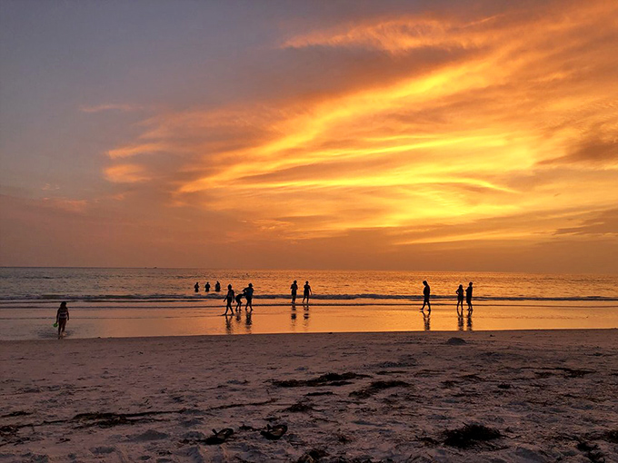 Mother Nature's nightly masterpiece turns the sky into a canvas of orange and gold, silhouetting beachgoers lucky enough to witness it.