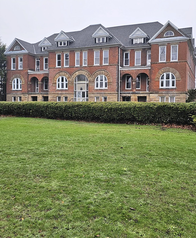 Manicured hedges and tidy landscaping can't quite mask the haunting presence of this imposing brick structure with its watchful windows.