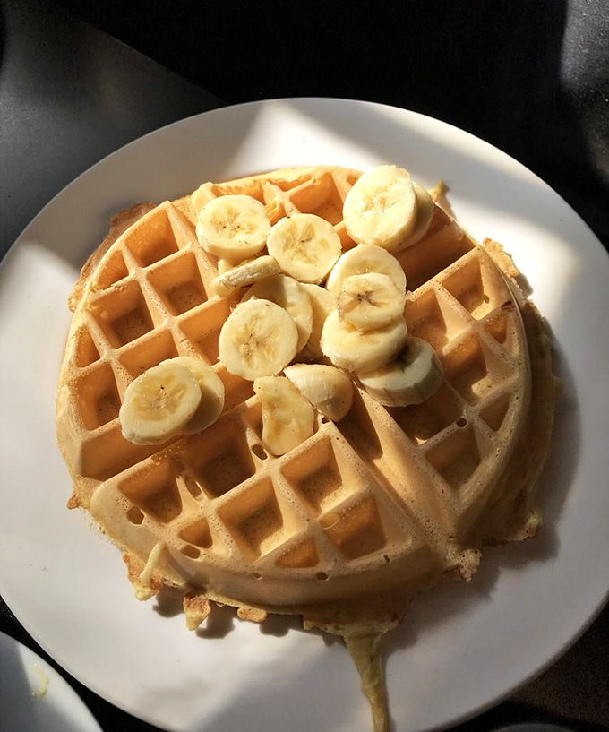A waffle that's achieved the perfect golden hue, topped with bananas that make you feel slightly virtuous about your indulgence.