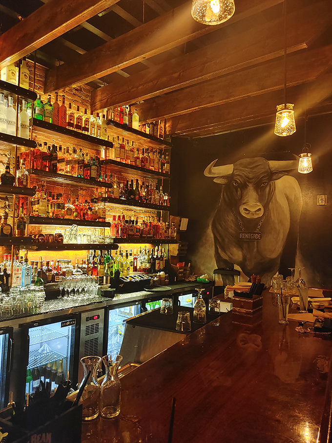 The bar area showcases an impressive spirits collection, while a magnificent bull mural watches over patrons like the patron saint of good decisions.