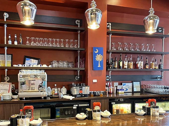 The bar area combines rustic industrial elements with warm wood tones, while the South Carolina flag reminds you exactly where this breakfast magic happens.