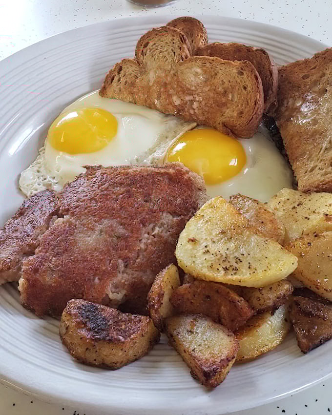 Corned beef hash with that perfect crust, sunny-side eggs, and home fries &ndash; the breakfast that launched a thousand productive mornings.