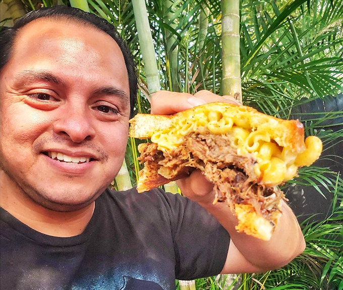Sometimes happiness is simply a man holding barbecue-topped mac and cheese against a backdrop of Florida palms.