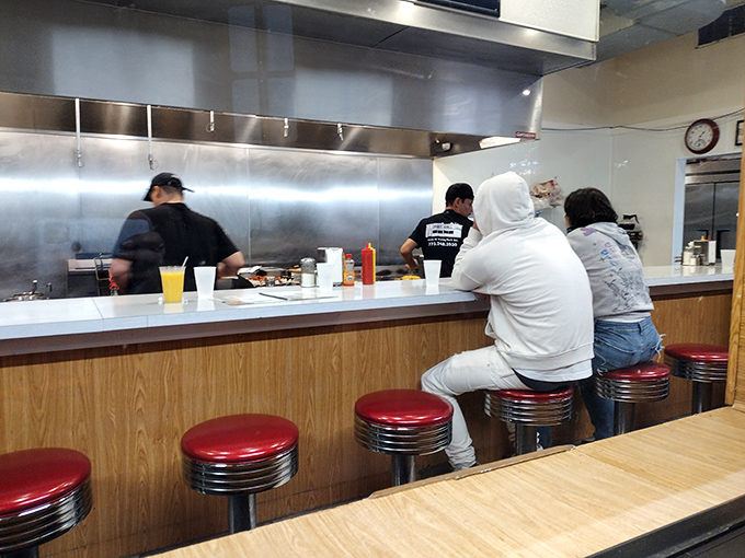 The counter ballet: where diners perch like birds on a wire, connected by the universal language of "pass the ketchup."