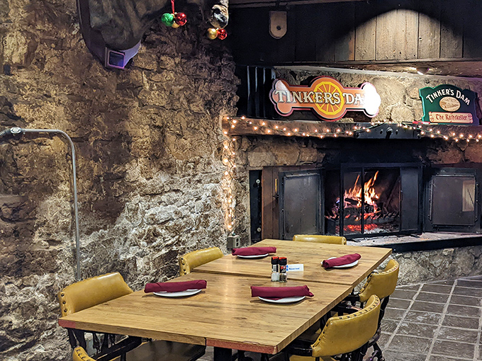 Stone walls, crackling fire, and "Tinkers Dam" sign create the kind of cozy dining nook that makes winter evenings memorable.