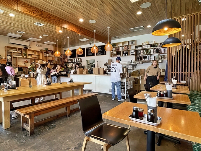 The dining room hums with the universal language of "mmm." Wooden tables, communal seating, and that ceiling—like dining in a modern treehouse for food enthusiasts.