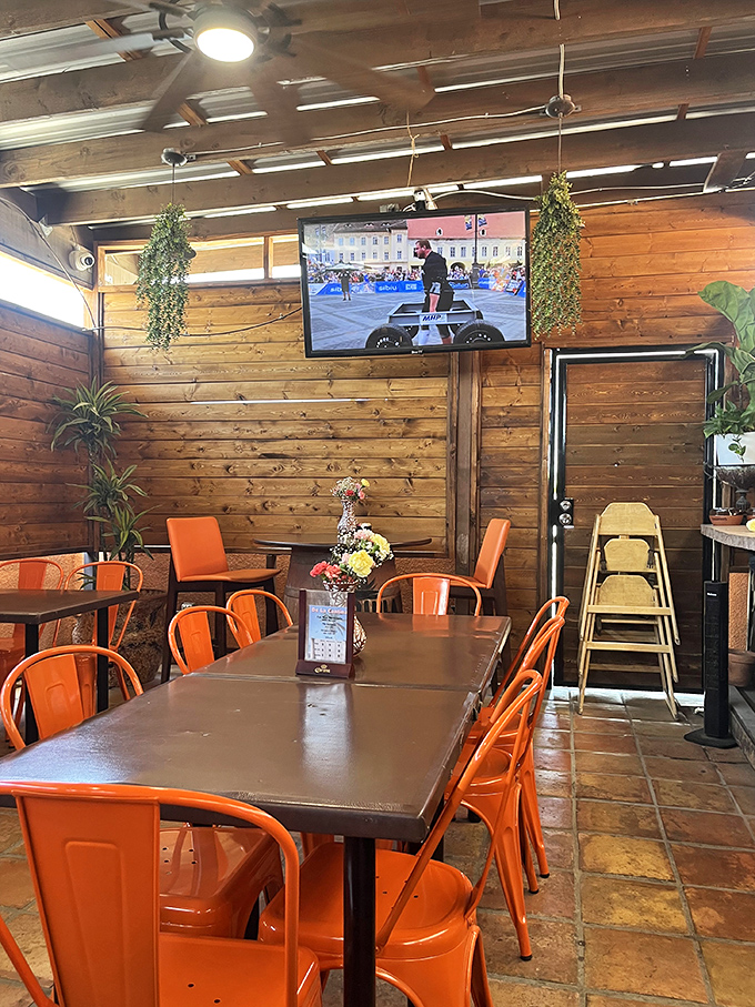 The dining room features wood-paneled walls and bright orange chairs that somehow make everything feel festive and welcoming at once.