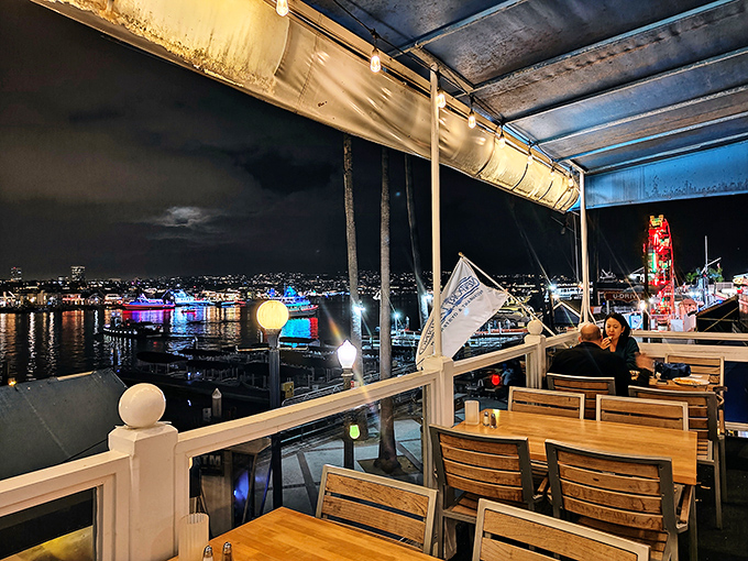 As night falls, the harbor transforms into a twinkling wonderland, visible from every table on Newport Landing's atmospheric outdoor deck.
