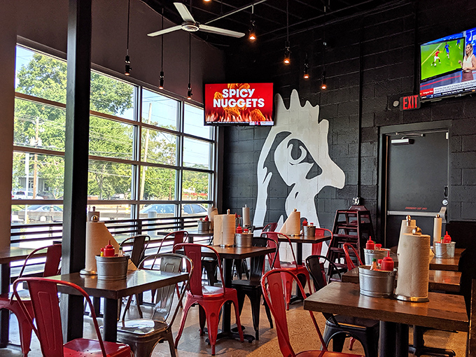 The dining room's chicken silhouette watches over patrons like a spicy guardian angel while red metal chairs invite you to stay awhile.