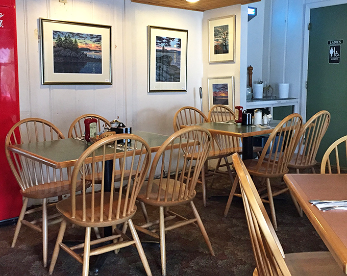 Local landscape photography adorns white walls while Windsor chairs await their next guests. Maine's natural beauty comes inside for breakfast.
