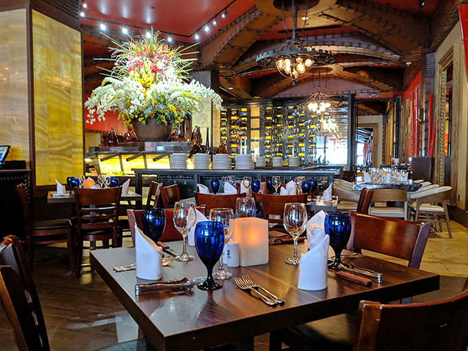 Elegant floral arrangements and warm lighting transform a meal into an occasion. The blue goblets add pops of color like sapphires on a dining crown.