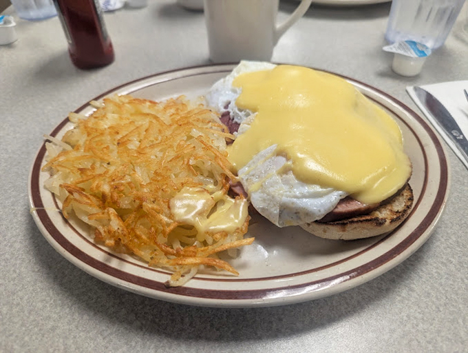 Eggs Benedict with a golden cheese blanket and hash browns so perfectly crisp they make a satisfying crunch you can almost hear through the photo.