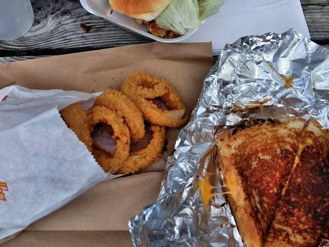 The humble grilled cheese gets the royal treatment with perfectly toasted bread and those onion rings standing guard like crispy sentinels.
