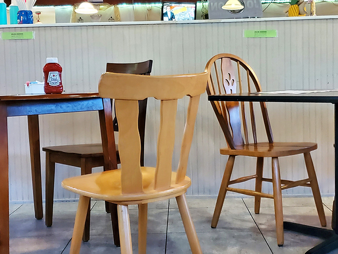 Mismatched wooden chairs and simple tables create that "grandma's dining room" vibe that makes comfort food taste even better.