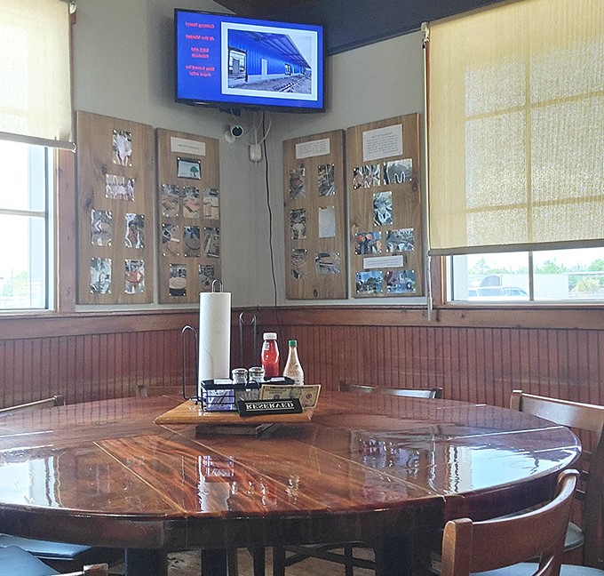 Round wooden tables where strangers become friends and food becomes memories. Notice the community photos on the wall.