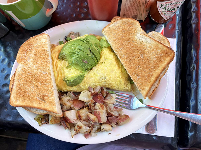 An omelet so perfectly folded it could teach origami classes, with avocado slices that California dreams are made of.