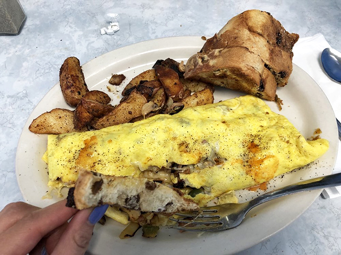 An omelet that knows its purpose in life is to deliver maximum flavor with minimum fuss. Those home fries look like they've been seasoned by someone who truly understands potatoes.