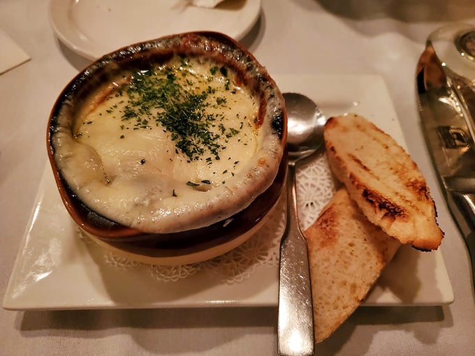 French onion soup that's wearing its cheese like a comfortable sweater. The toasted bread islands are just waiting for exploration.