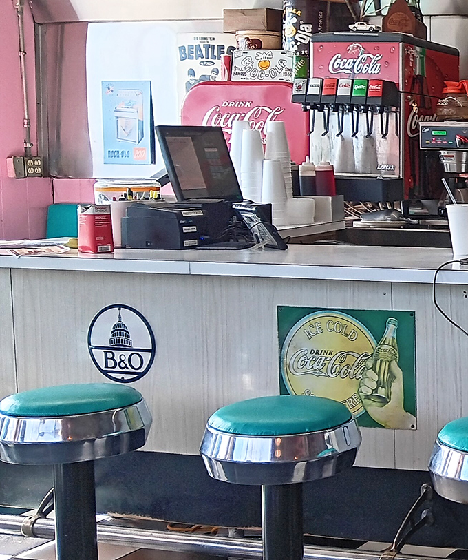 The soda fountain counter with its classic Coca-Cola dispenser stands ready to fulfill your fizzy dreams, while those turquoise stools invite you to spin like it's 1955.
