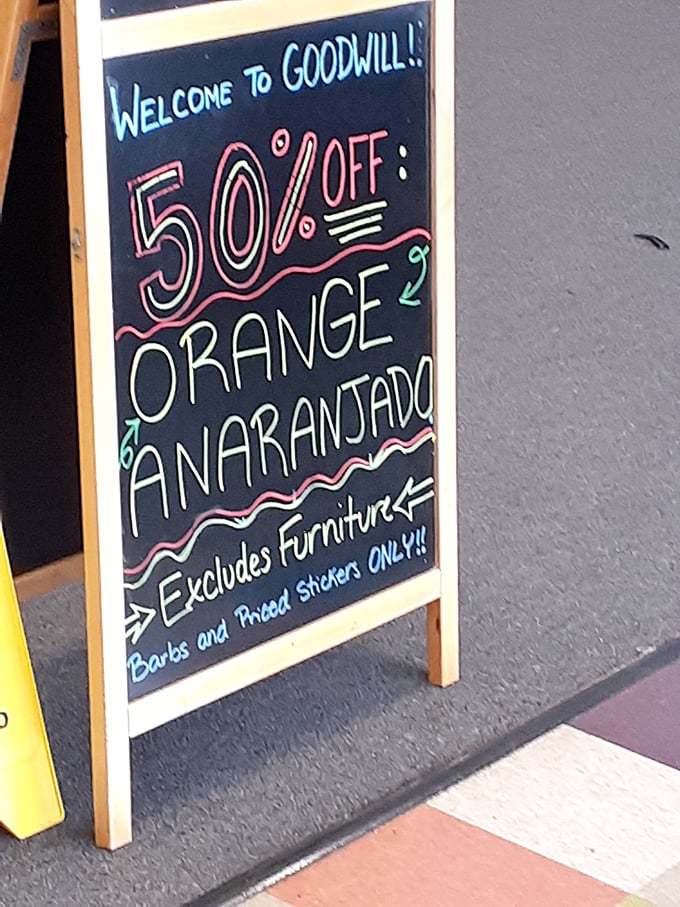 The chalkboard speaks truth: 50% off orange tags today. In thrift store mathematics, that's practically being paid to shop!