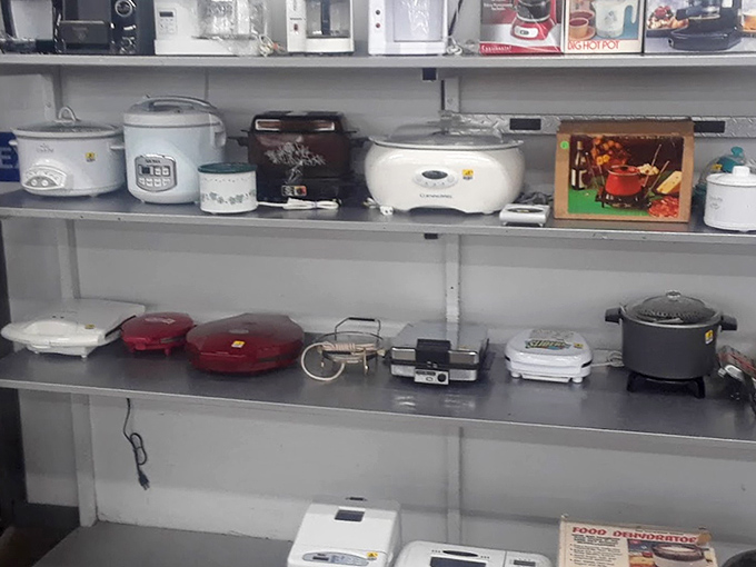 A small army of rice cookers, slow cookers, and kitchen gadgets stands at attention. One person's appliance redundancy becomes another's culinary opportunity.