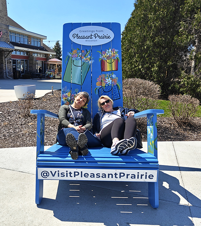 The universal shopping recovery position: two weary bargain hunters recharging on Pleasant Prairie's signature blue bench before the next retail round.