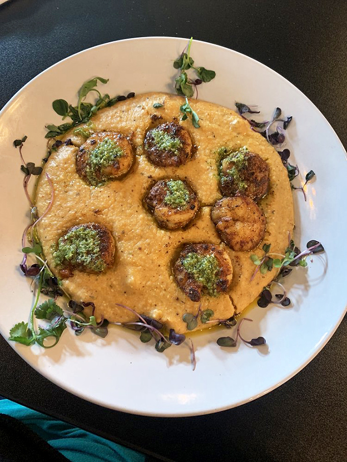 Scallops nestled in creamy grits like pearls in velvet. The bright herb oil adds a pop of color and flavor that makes this dish ready for its close-up.