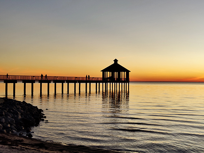 Sunset specialists at work. The silhouetted pier and gazebo create the kind of moment that makes smartphone photographers feel like professionals.