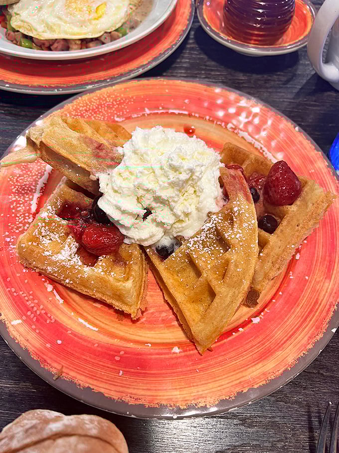 Waffle architecture at its finest. Crisp exterior, fluffy interior, crowned with fresh berries and whipped cream &ndash; a breakfast that's both art and comfort.