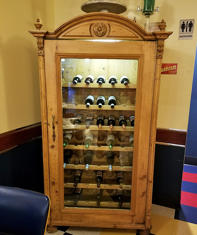 The antique wine cabinet stands like a wooden sentinel, guarding grape-based treasures for those seeking liquid courage.