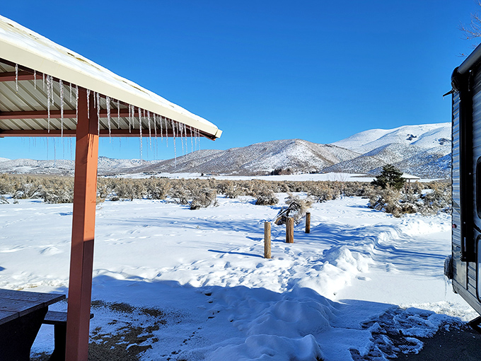 Winter transforms the park into a serene wonderland. Icicles hanging from cabin eaves frame a vista of snow-covered mountains.