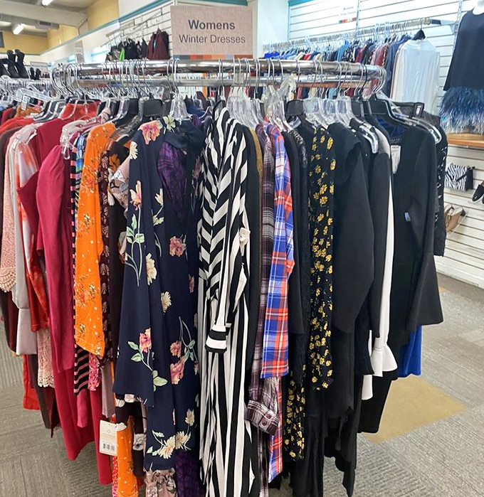 The women's dress section blooms with forgotten florals and patterns. Each hanger tells a story of a vacation outfit that never made its debut.