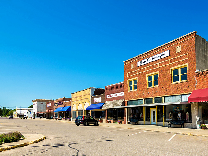 Red brick buildings with colorful awnings create a vibrant main street that's pure small-town perfection.