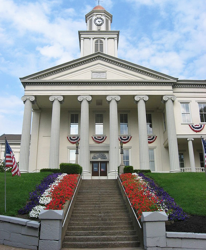 Stately columns and patriotic bunting welcome visitors to New Castle's historic courthouse. American flags flutter against the classical white facade.