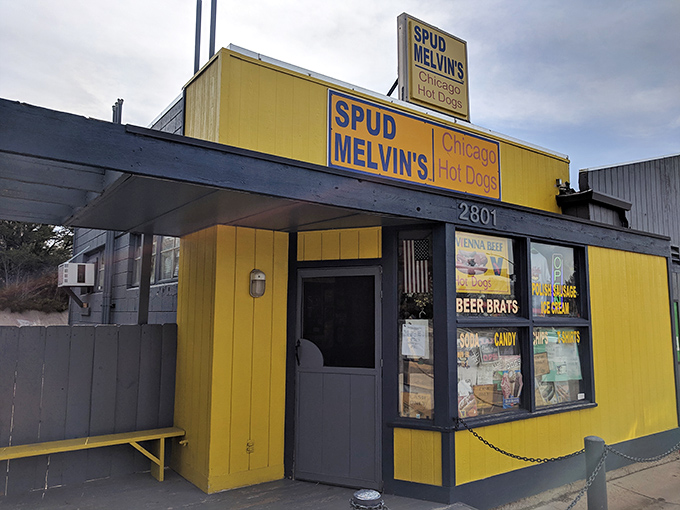 Spud Melvin's sunny yellow exterior with bold blue signage stands out like a cheerful beacon for hot dog lovers.