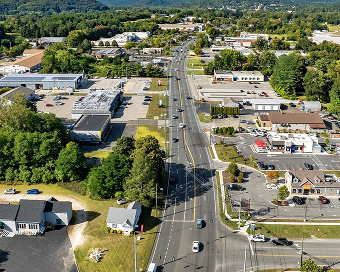 Wide commercial avenue lined with shopping centers and parking areas creates convenient suburban living at reasonable costs.