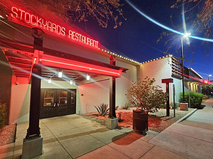 The iconic red neon sign of The Stockyards glows like a beacon for beef lovers, promising carnivorous delights within those unassuming white walls.