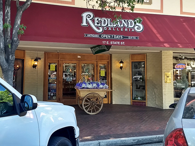 The iconic red awning of Redlands Galleria beckons like a time portal, complete with an antique flower cart that practically whispers, "Come in, the past is waiting."